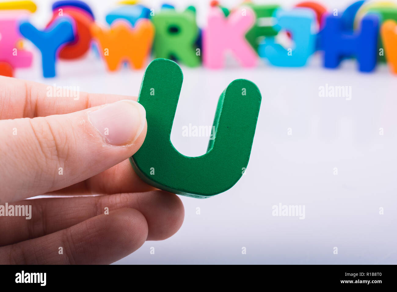 Hand holding letter cube U of made of wood Stock Photo - Alamy