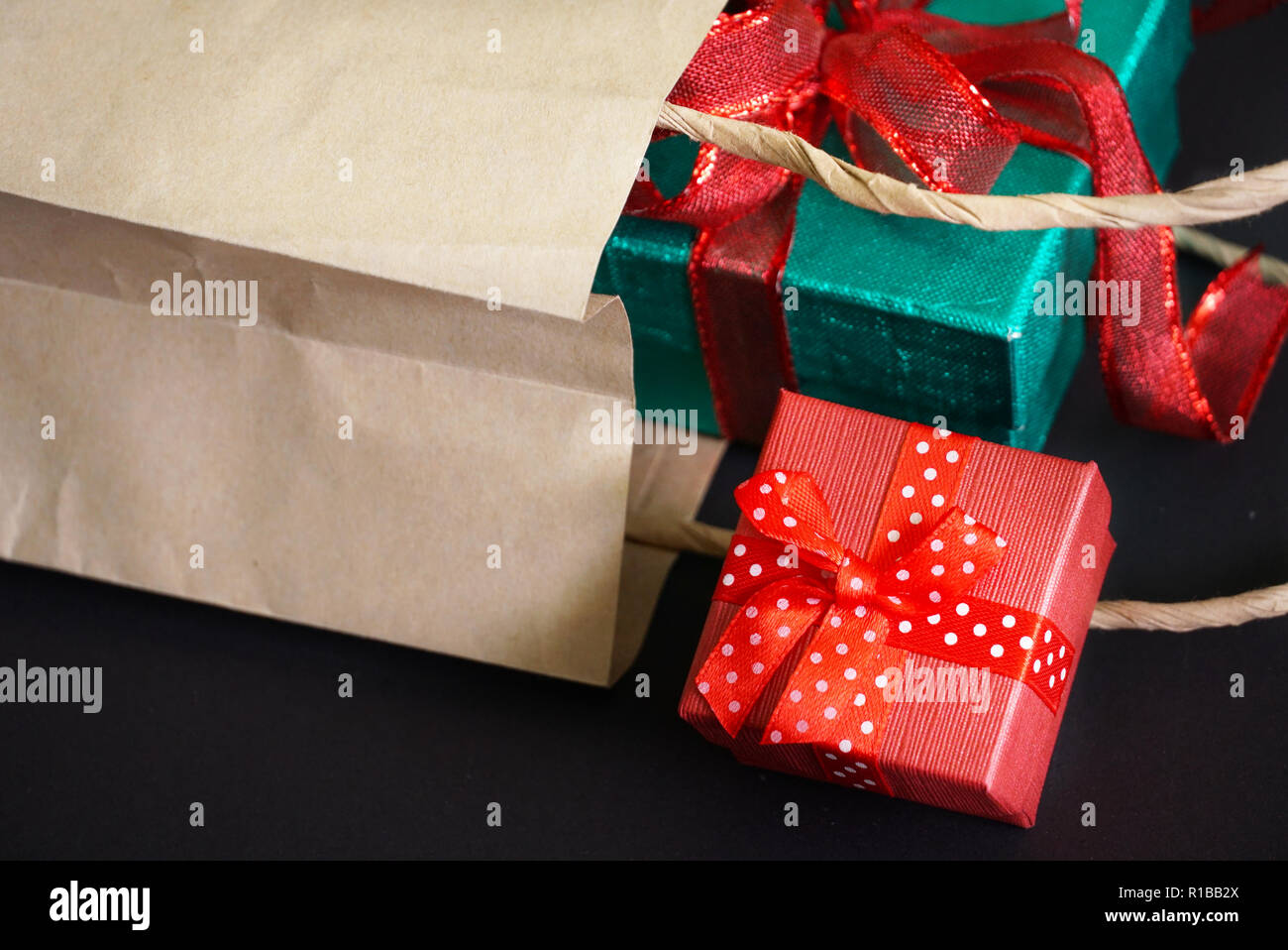 Gift boxes spill out from bag on the black background for shopping ...