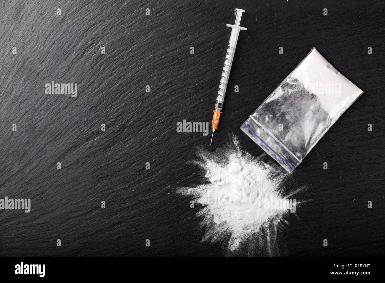powder drugs and a syringe on a black background. view from above ...
