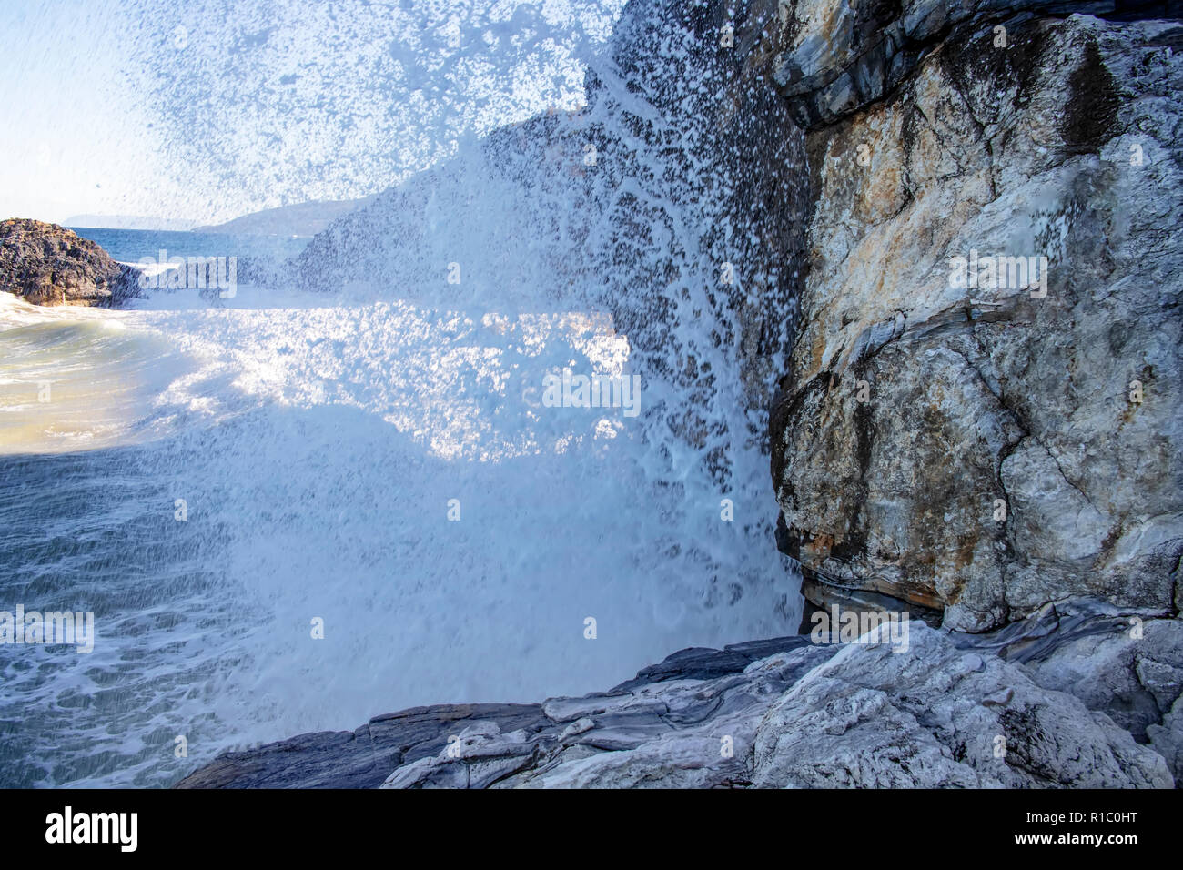 Splashes of water from the sea wave crashed against the stone cliff ...