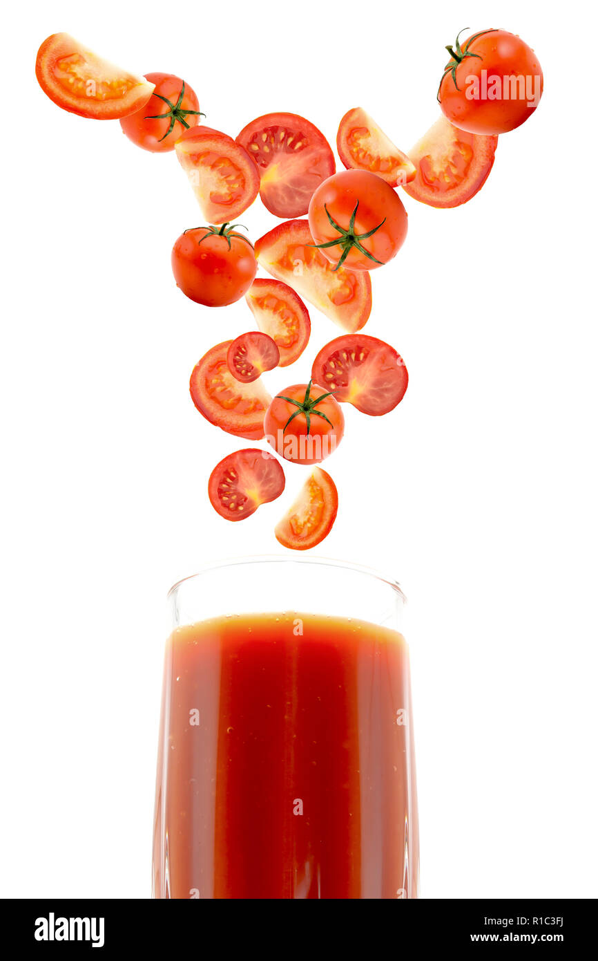 Falling sliced tomatoes in glass of tomato juice isolated on white ...