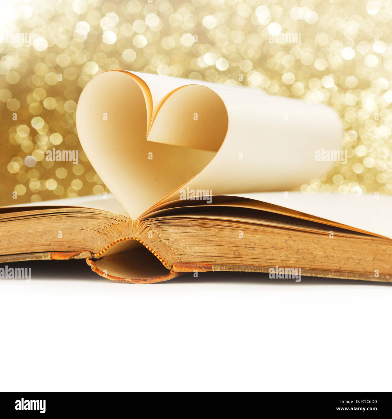 Pages of open book rolled in heart shape on glitter background Stock ...