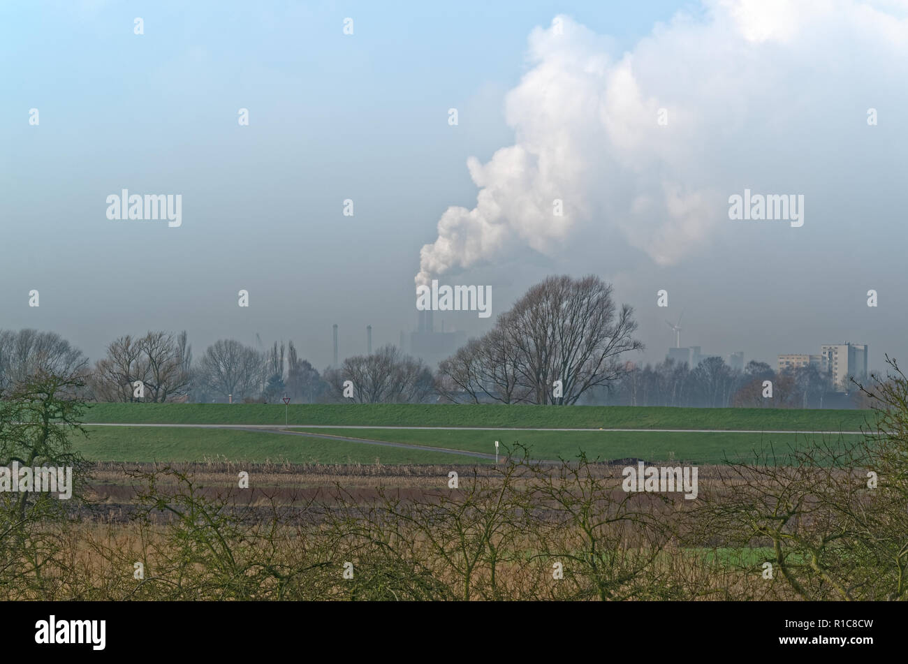 landscape view of green meadow and smock from industrial chimney ...