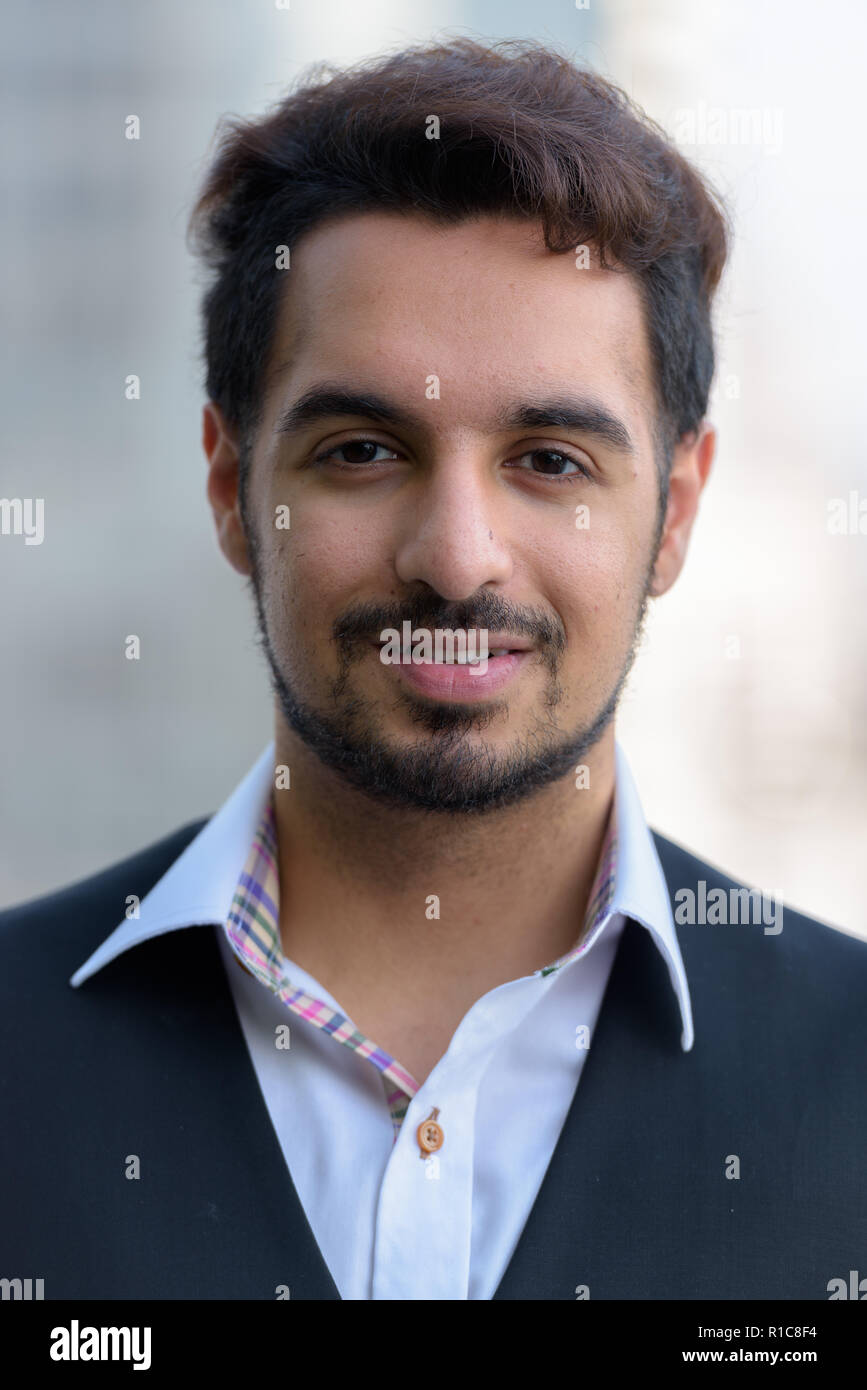 Face of young happy Indian man smiling outdoors in the city Stock Photo ...