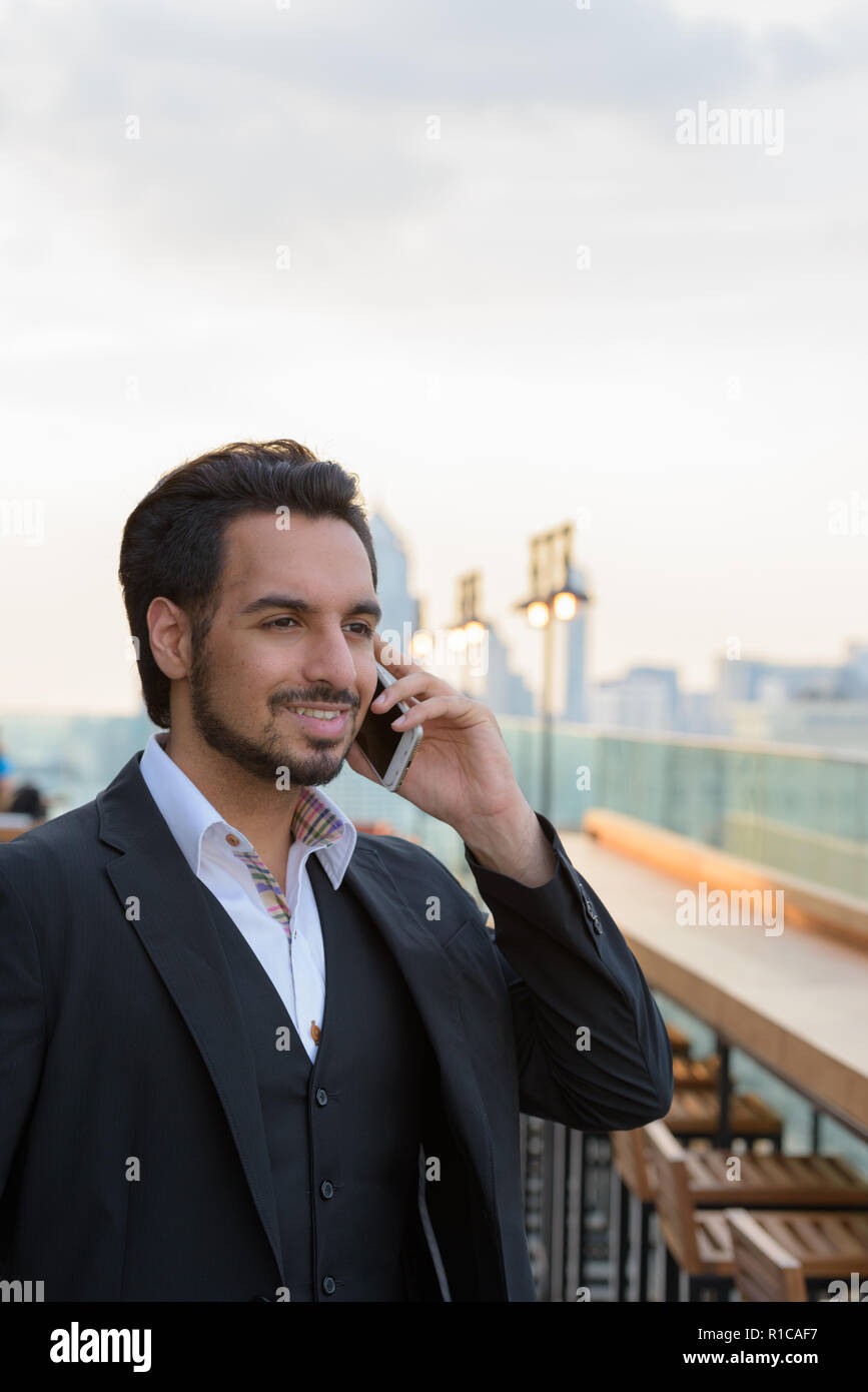 Thoughtful young happy Indian businessman smiling while talking Stock ...
