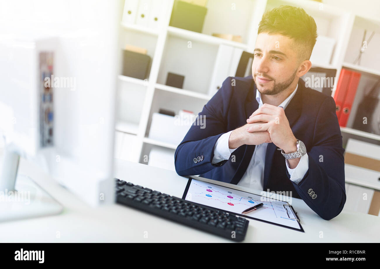 A young man sitting in the office at a computer Desk and working with ...