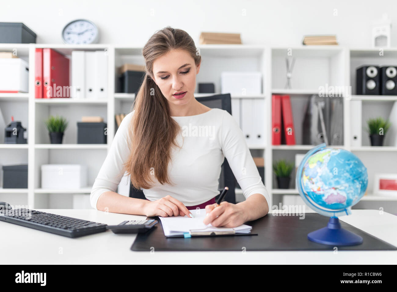 A young girl sitting at a table and writing on a piece of paper Stock ...
