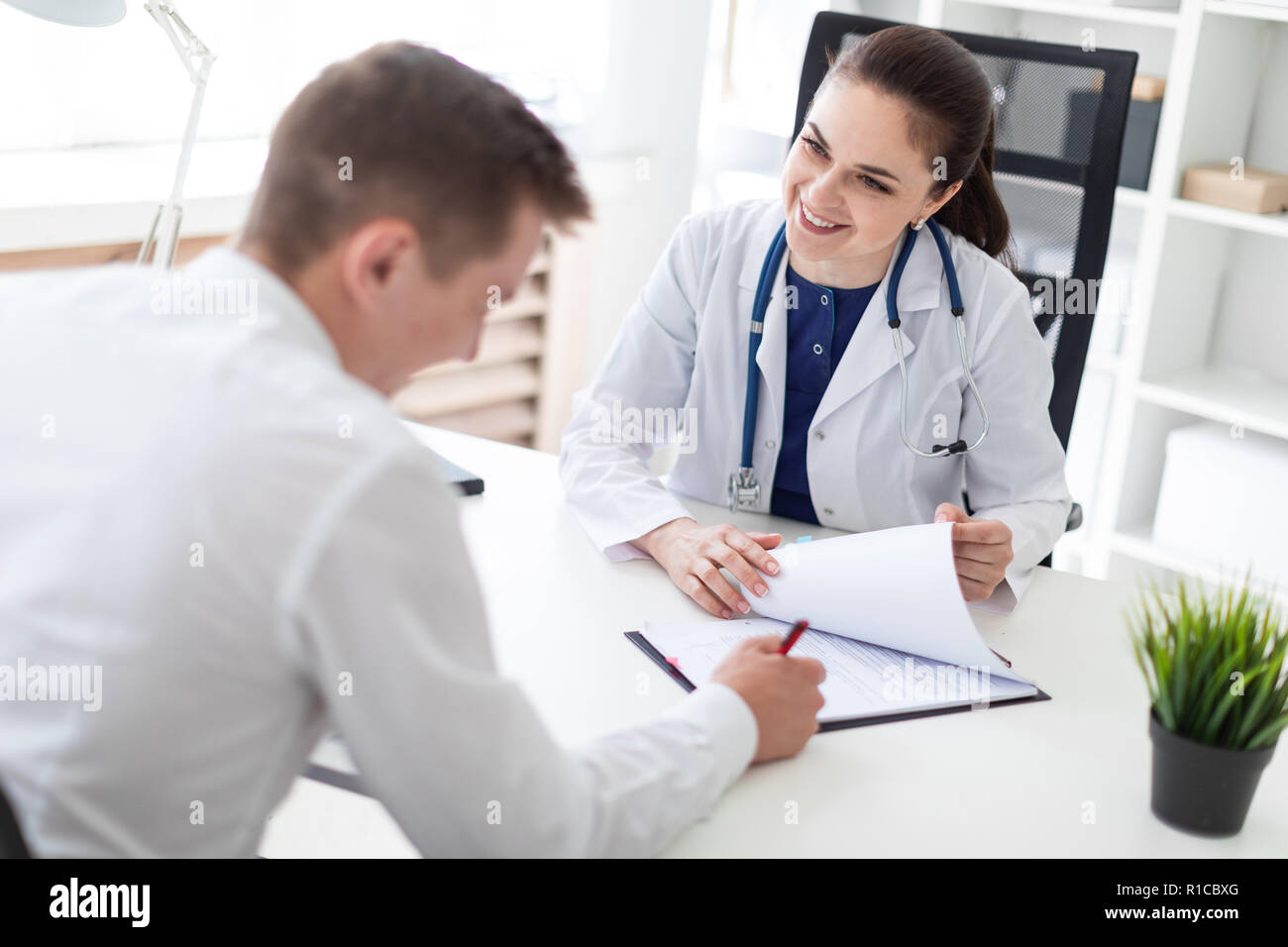 The young man at the doctor's office signs the documents Stock Photo ...