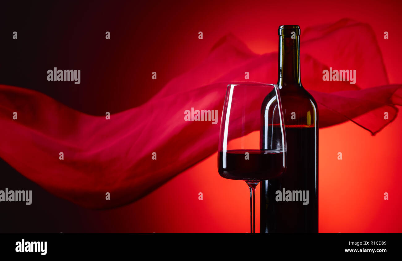 Glass and bottle of red wine on a red background. Red sheer fabric ...