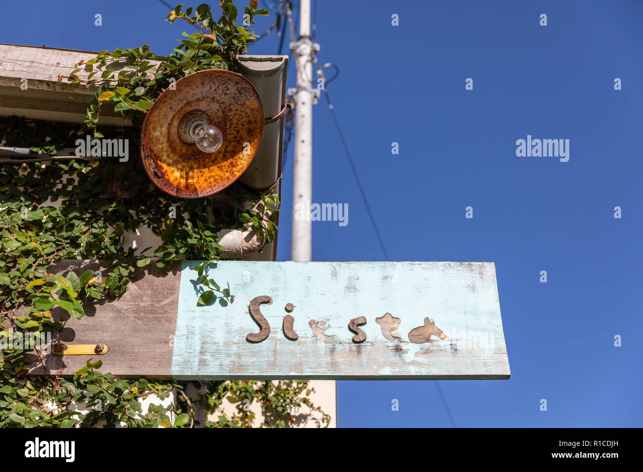 Weather-beaten wooden 'Siesta' sign, pastel-coloured, rusty lamp and ...