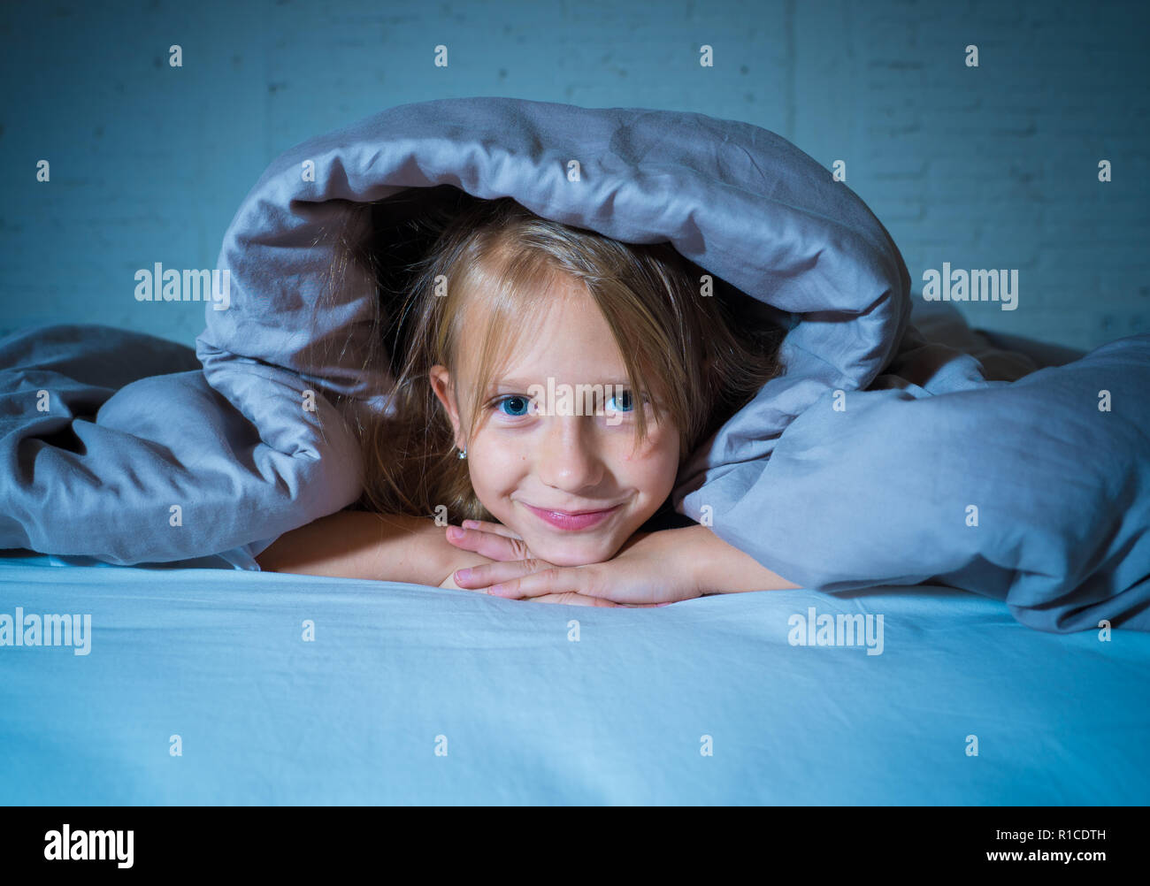Smiling and cheerful sweet small girl looking happy lying in bed at ...