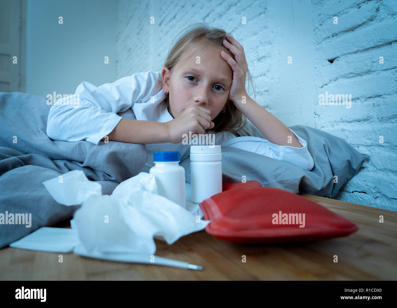 Sweet sick cute girl feeling sick lying in bed with medicines ...