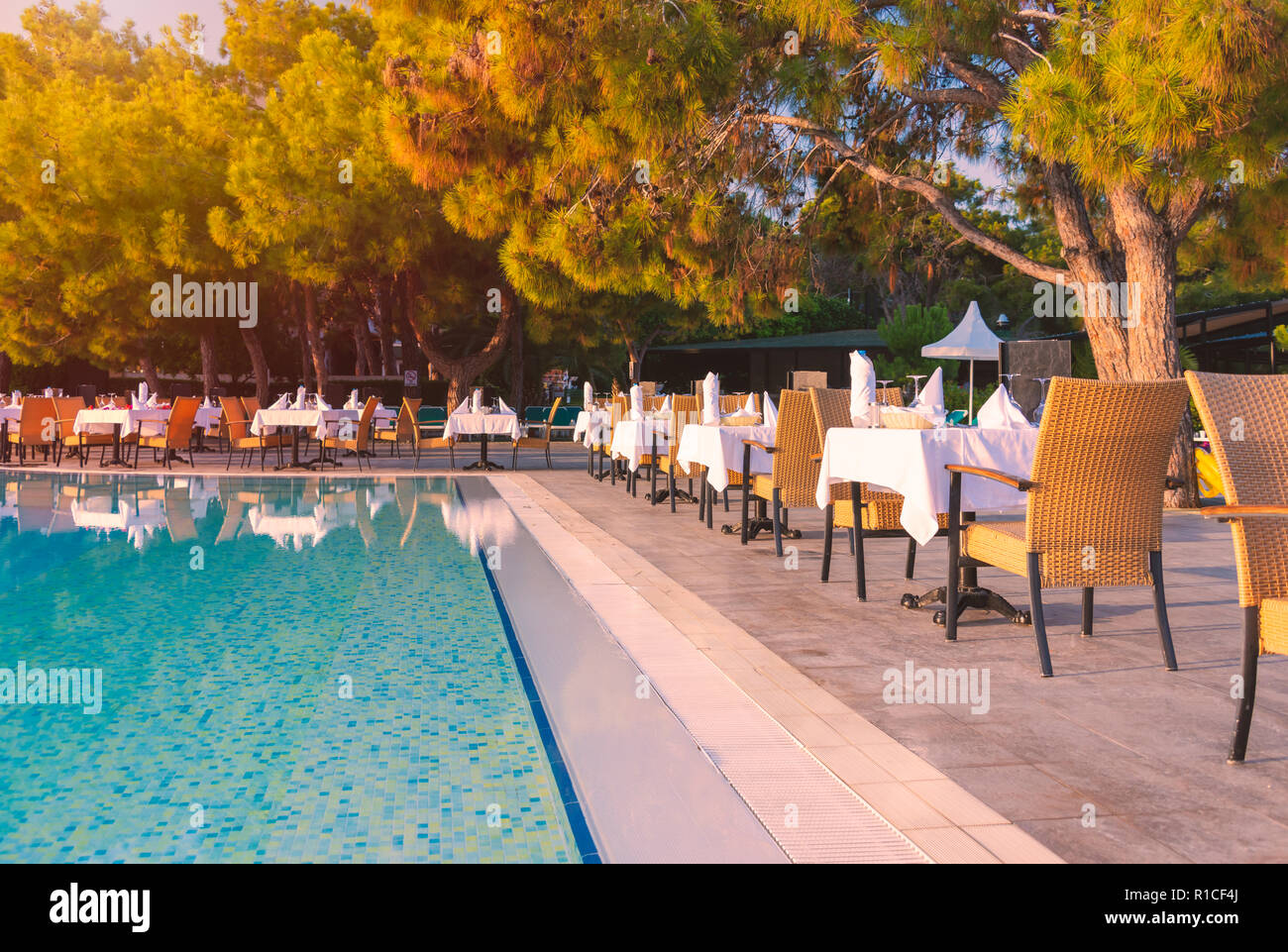 Chairs and table near pool at hotel restaurant. Cutlery and napkings on ...