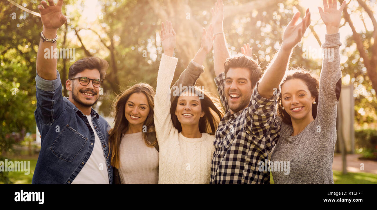 A happy group of friends in the park having fun with arms on the air ...