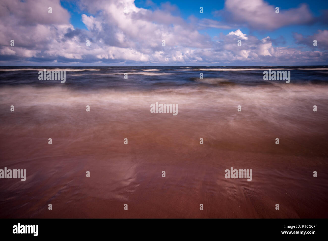 long exposure sea beach with rocks and washed out waves of water ...
