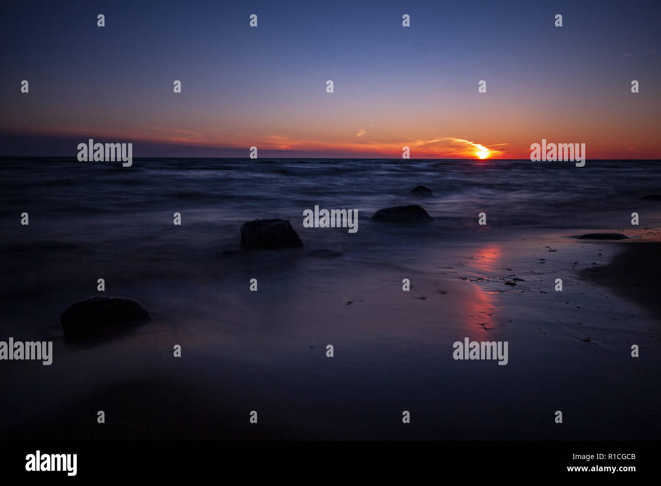 long exposure sea beach with rocks and washed out waves of water ...