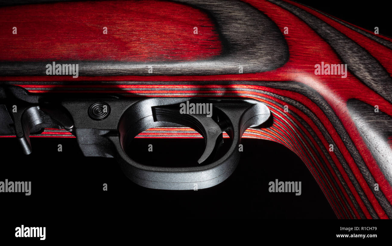 Red laminated rifle trigger on a black background Stock Photo - Alamy