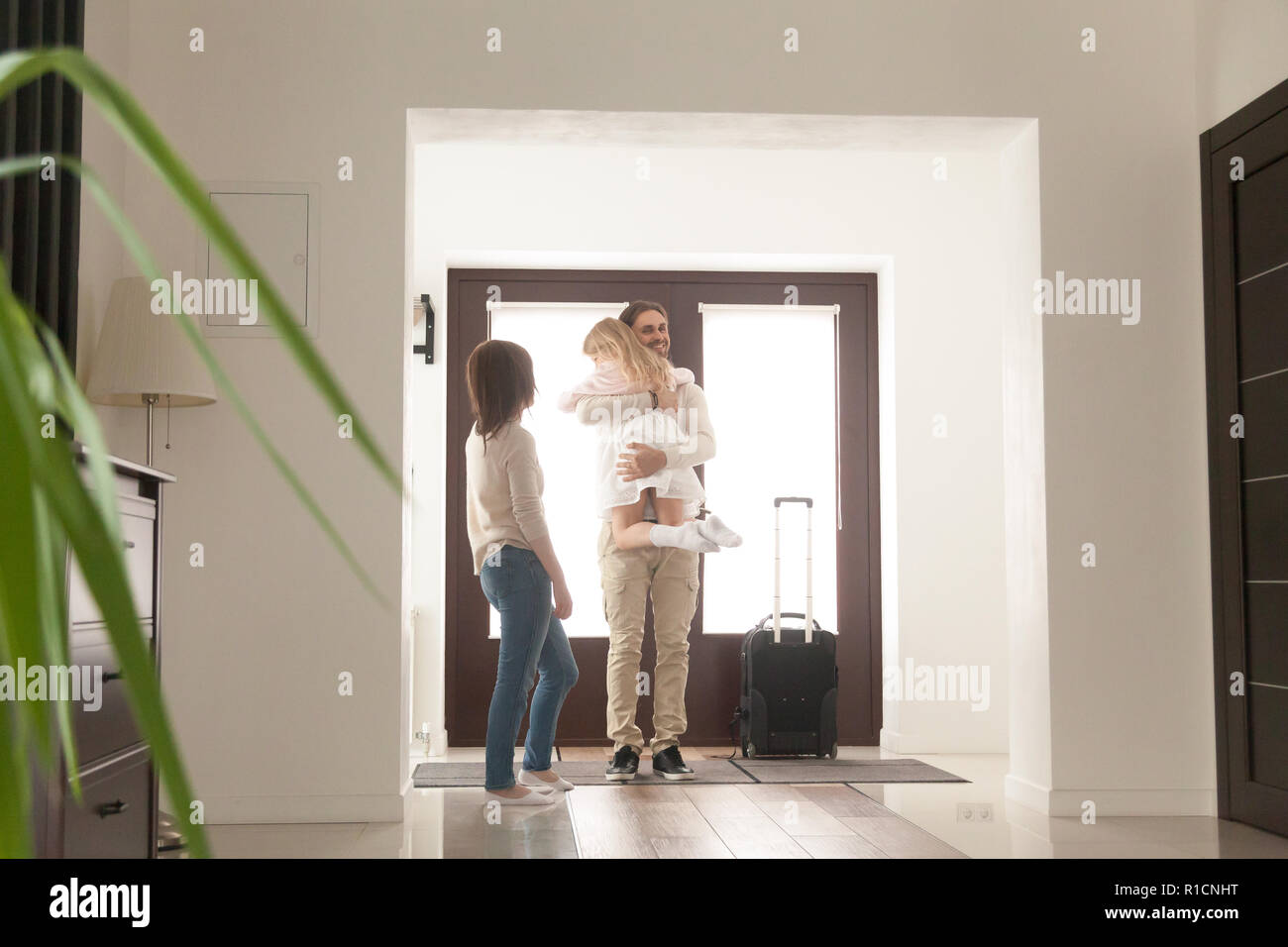 Happy family hugging in hallway at home Stock Photo - Alamy