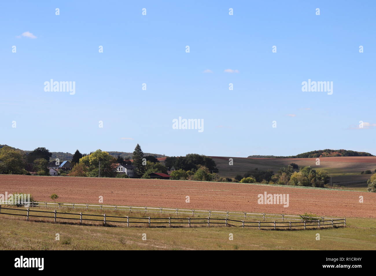 Open fields surrounding a farmhouse and recently plowed garden Stock ...