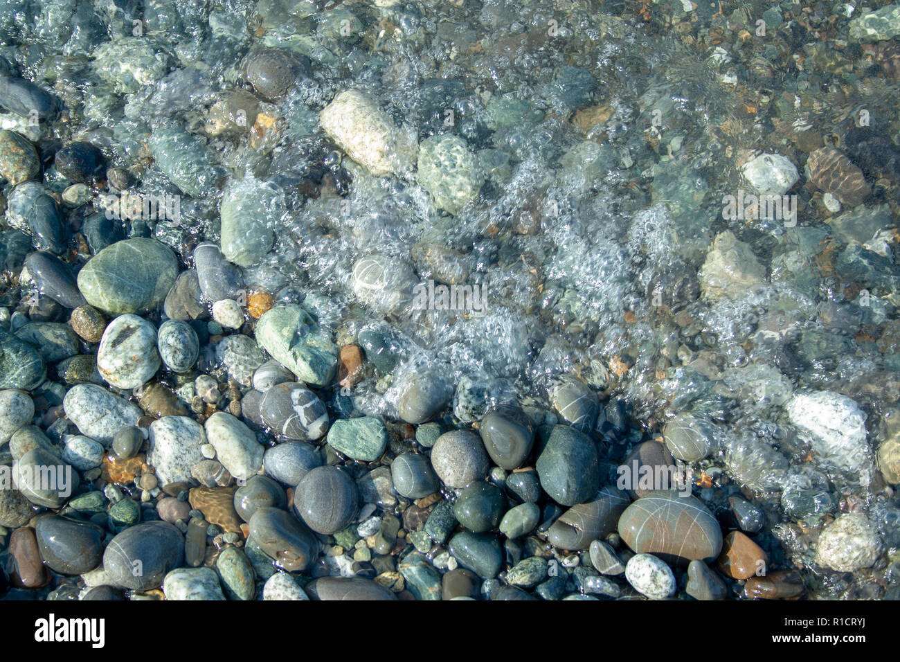 Stone beach with waves. Multi colore stones on beach Stock Photo - Alamy