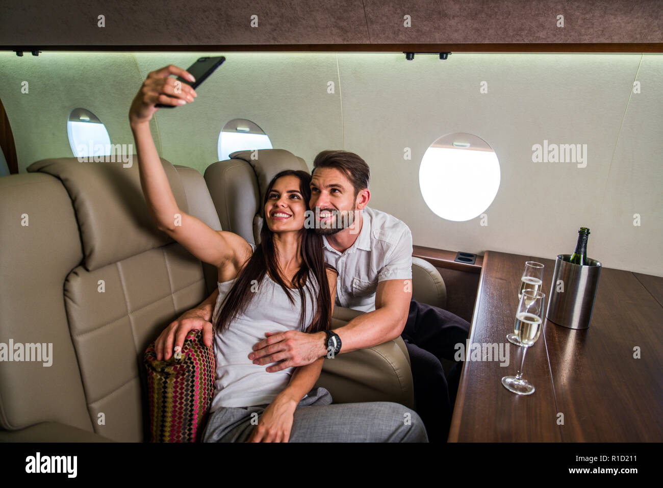 Happy couple travelling on a luxury private jet - Young adults travel ...