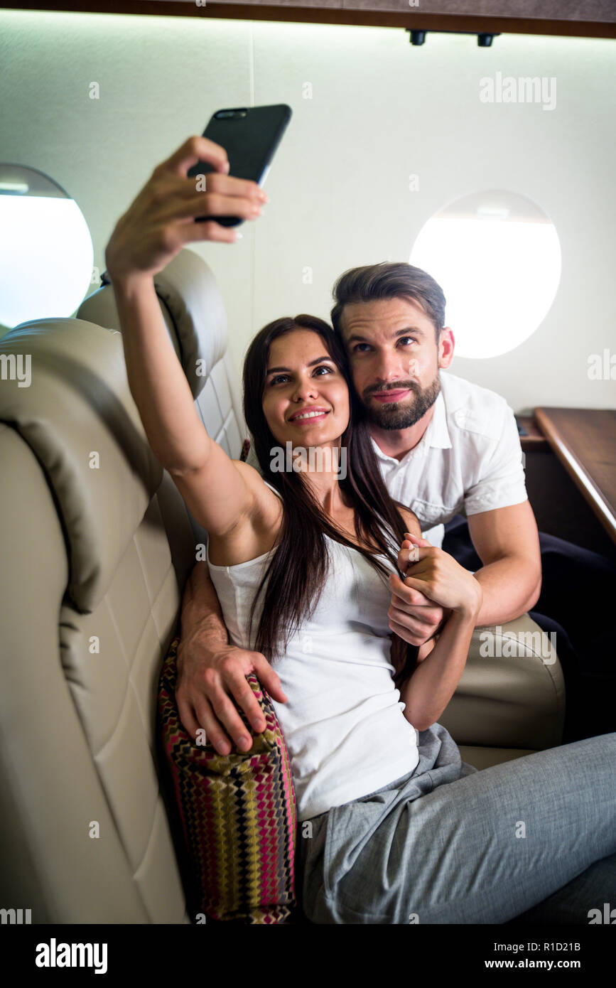 Happy couple travelling on a luxury private jet - Young adults travel ...