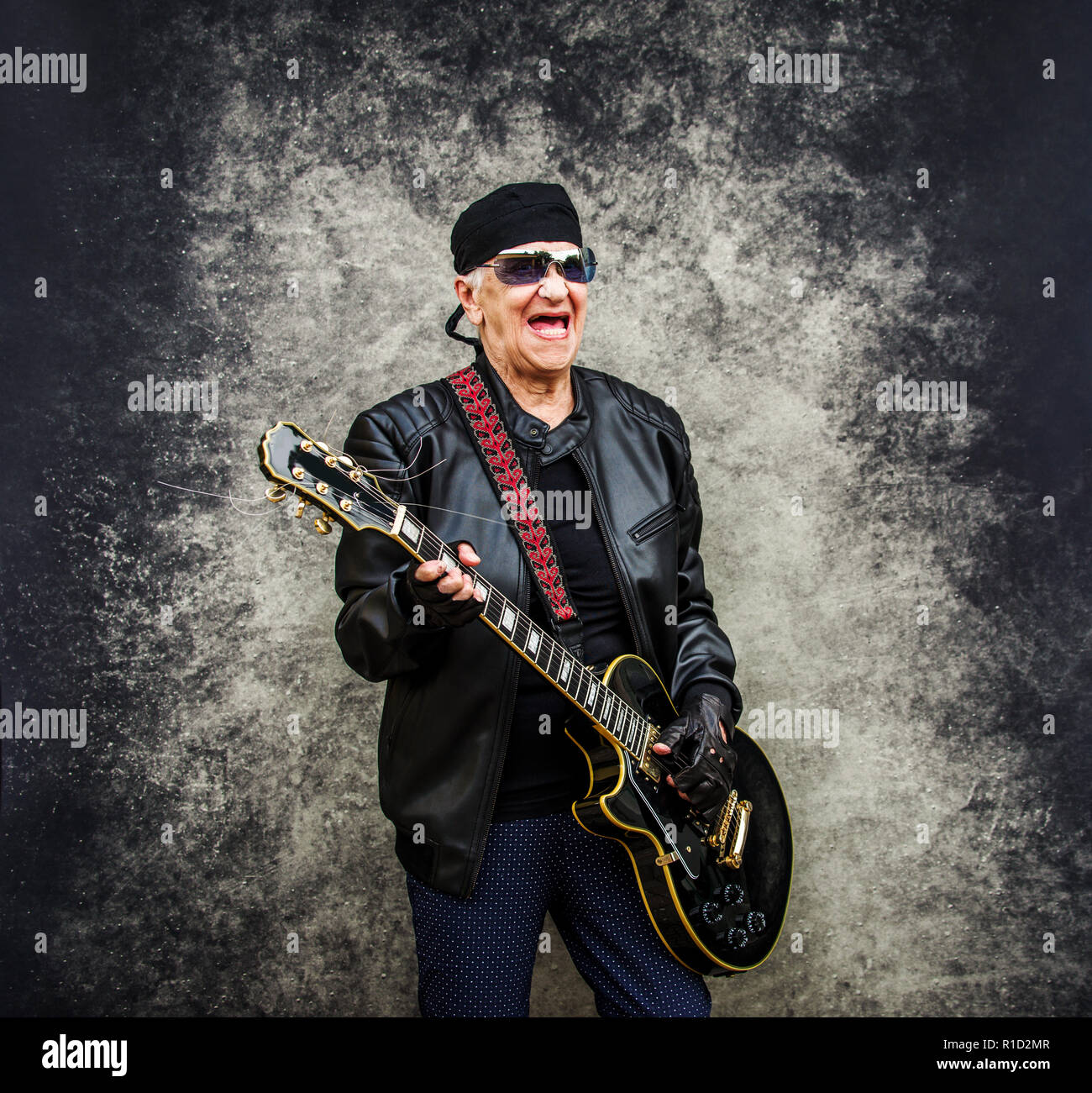 Funny and extravagant senior woman posing on colored background ...