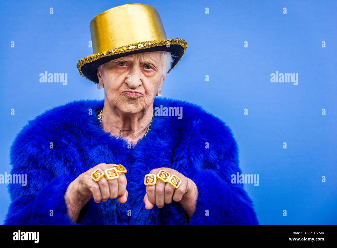 Funny and extravagant senior woman posing on colored background ...