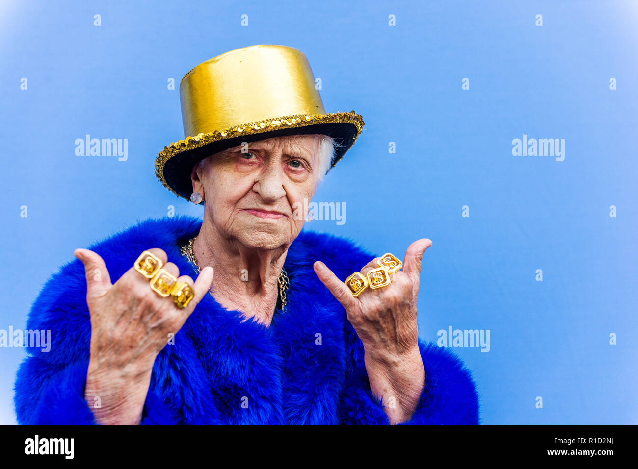 Funny and extravagant senior woman posing on colored background ...