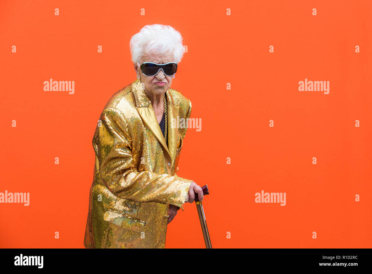 Funny and extravagant senior woman posing on colored background ...