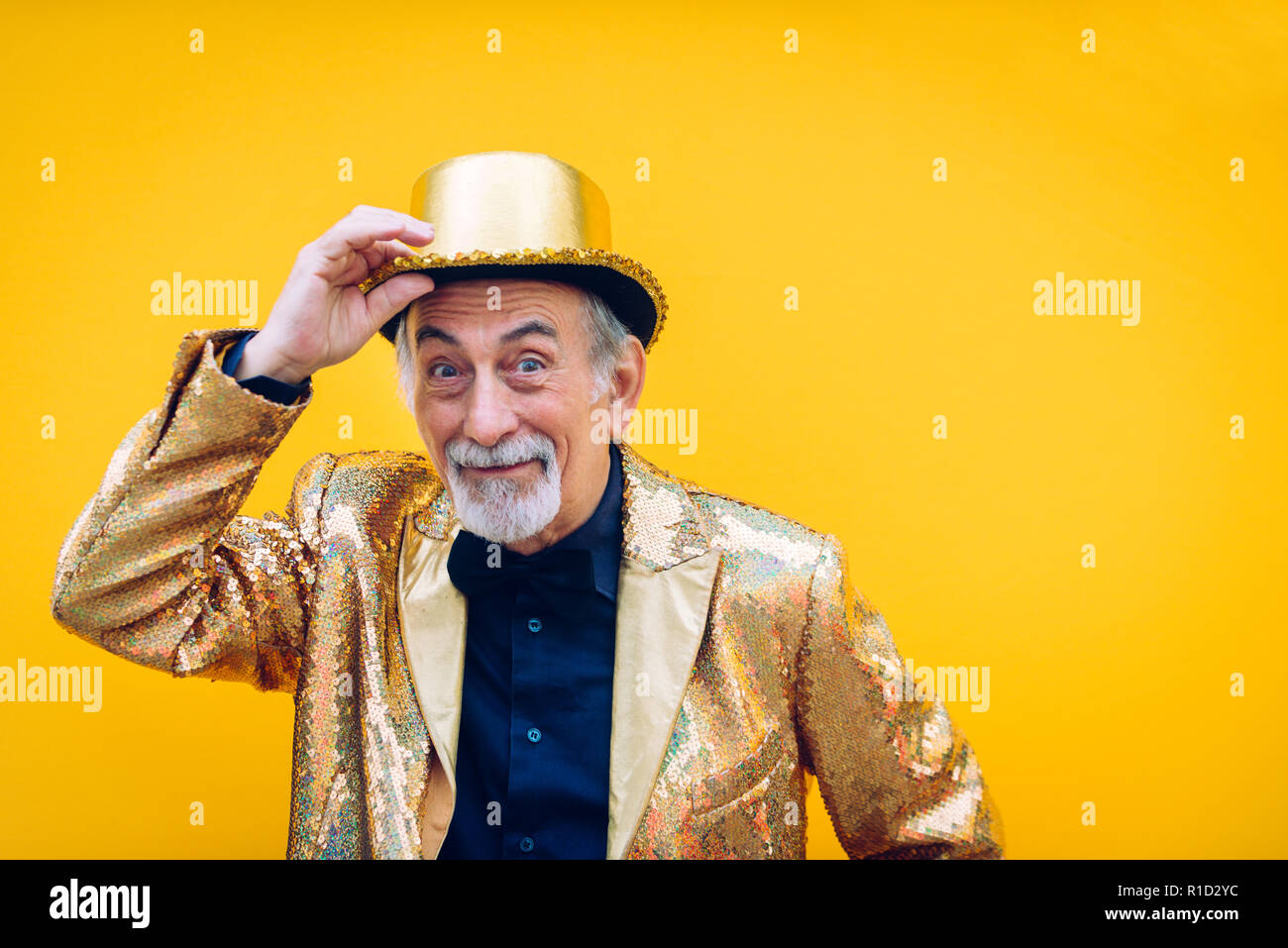 Funny and extravagant senior man posing on colored background ...