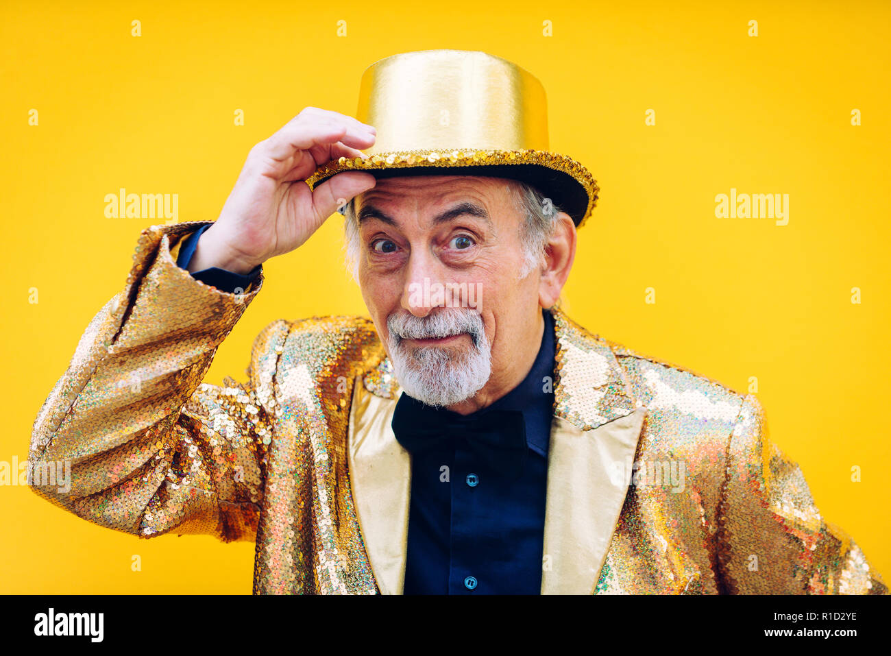 Funny and extravagant senior man posing on colored background ...