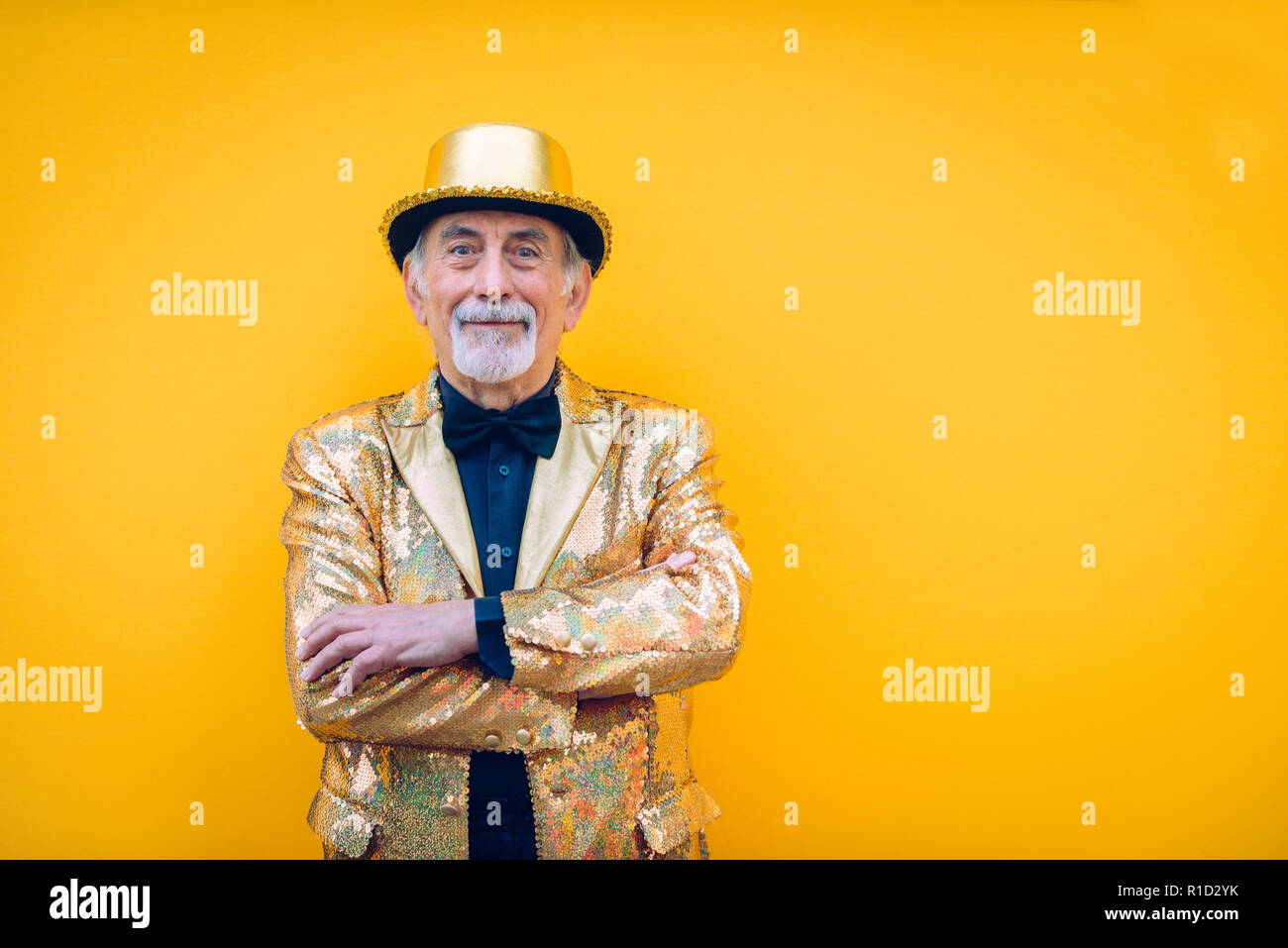 Funny and extravagant senior man posing on colored background ...