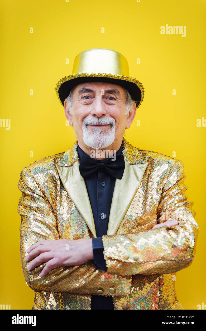 Funny and extravagant senior man posing on colored background ...