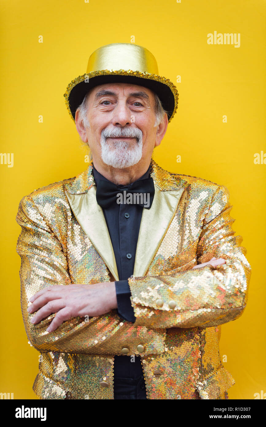 Funny and extravagant senior man posing on colored background ...