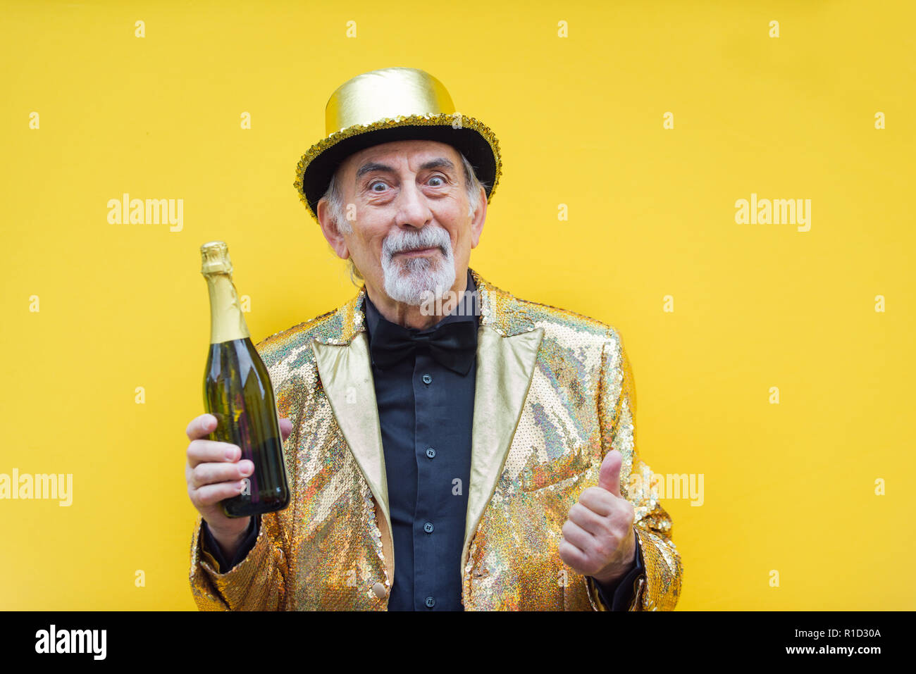 Funny and extravagant senior man posing on colored background ...
