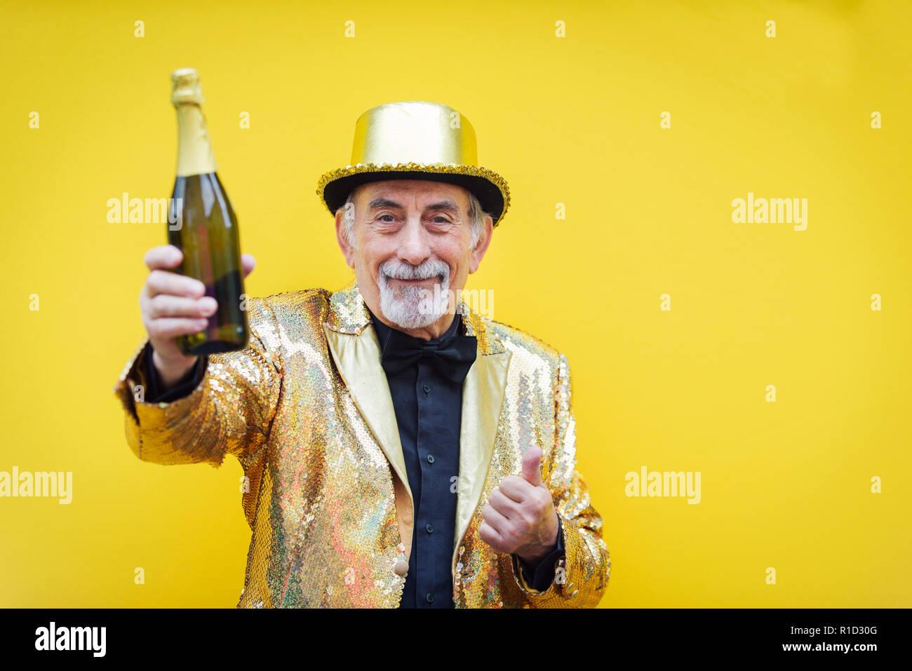 Funny and extravagant senior man posing on colored background ...