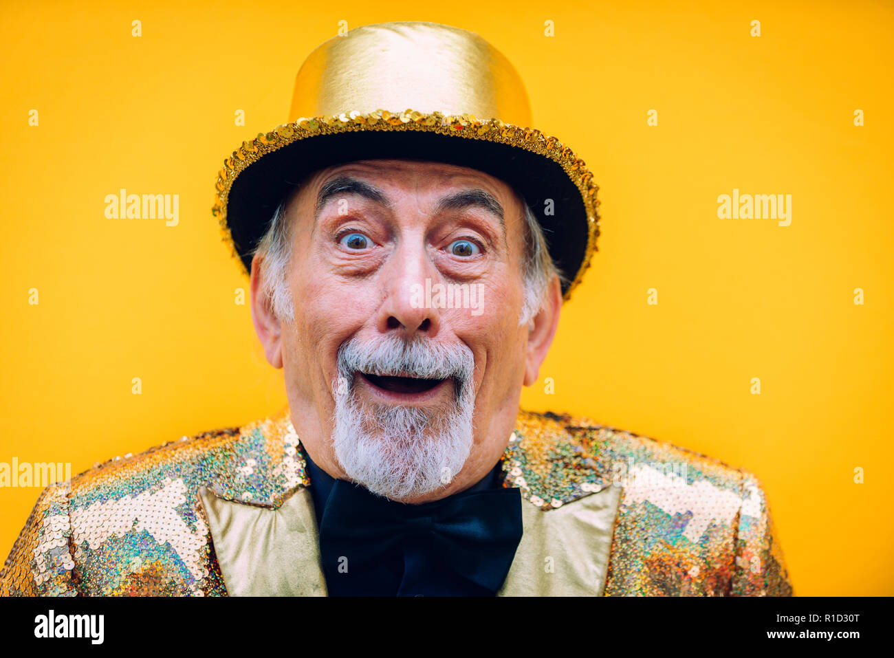 Funny and extravagant senior man posing on colored background ...