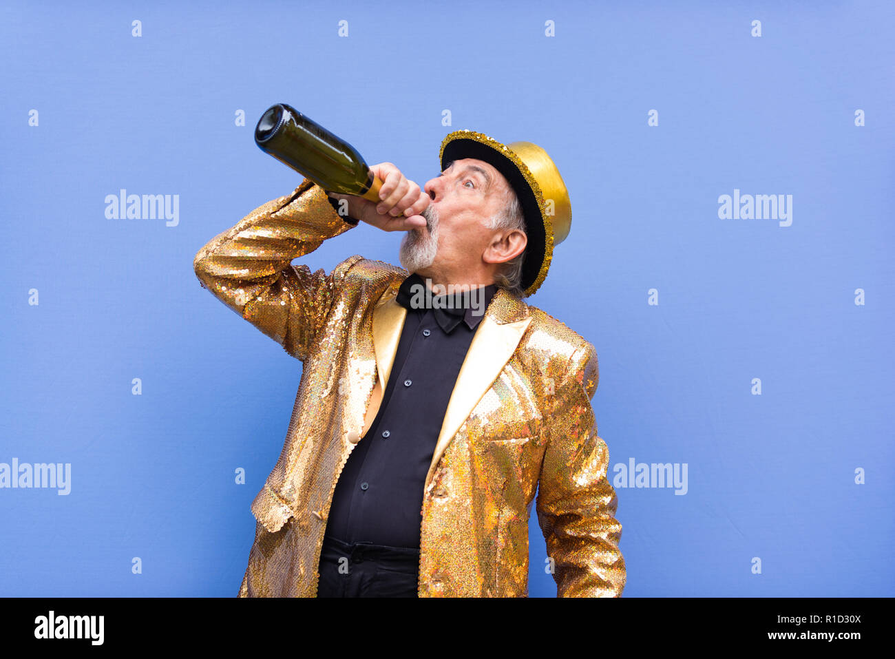 Funny and extravagant senior man posing on colored background ...