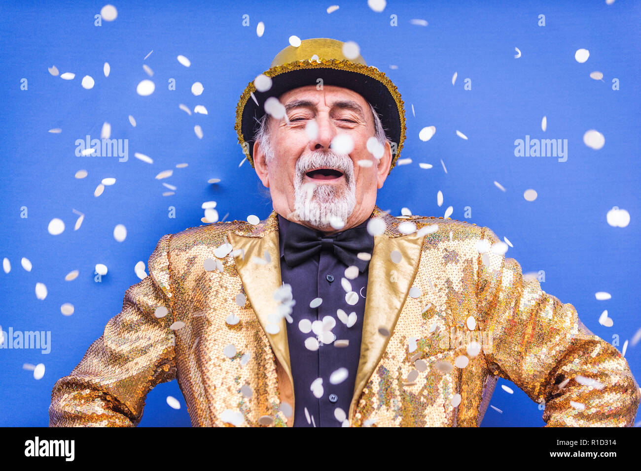 Funny and extravagant senior man posing on colored background ...