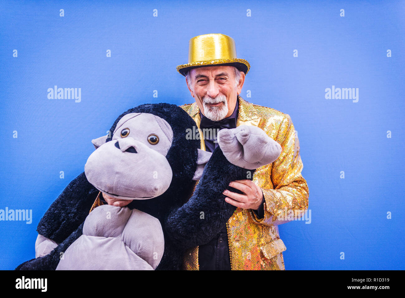 Funny and extravagant senior man posing on colored background ...