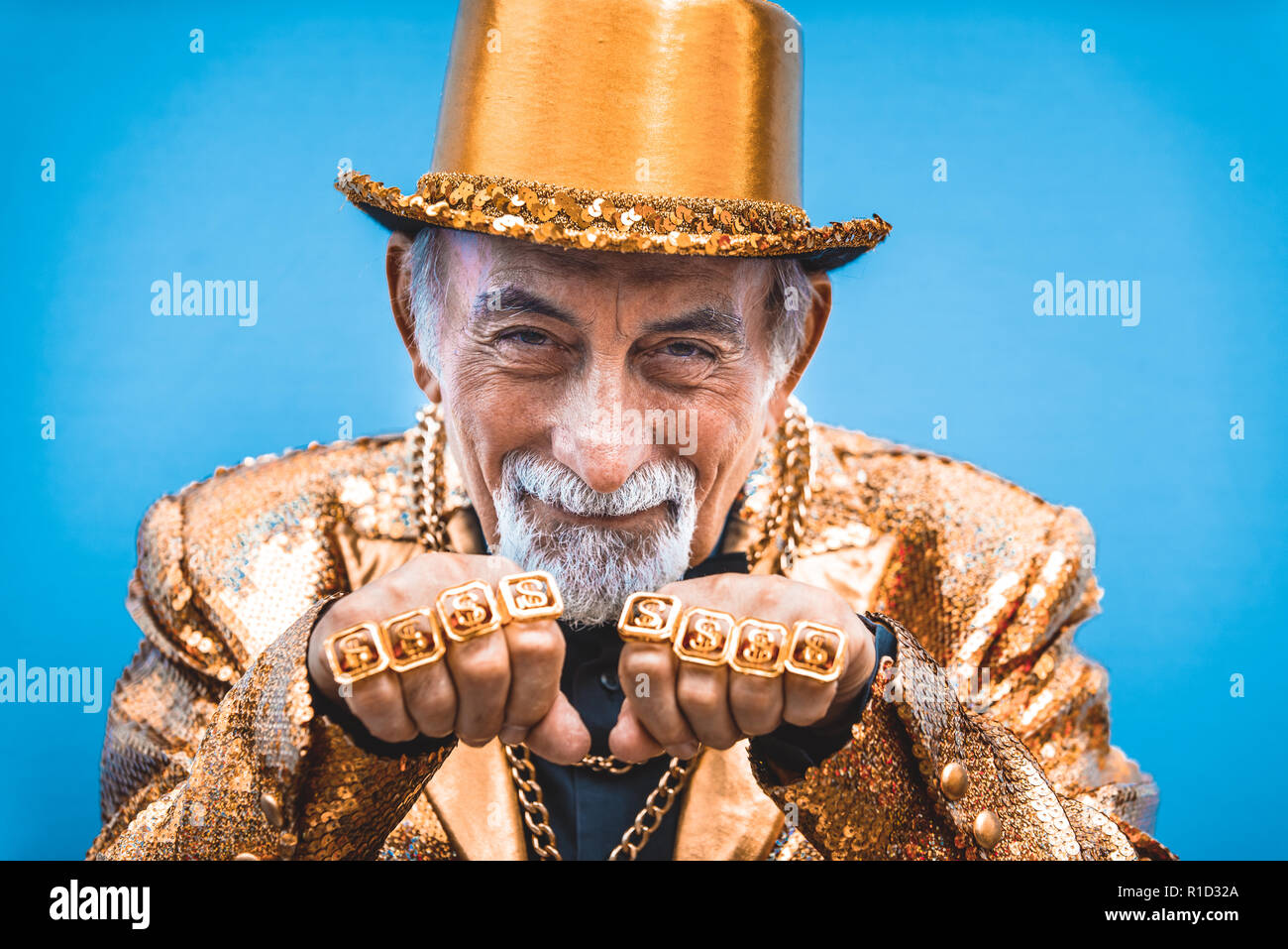 Funny and extravagant senior man posing on colored background ...