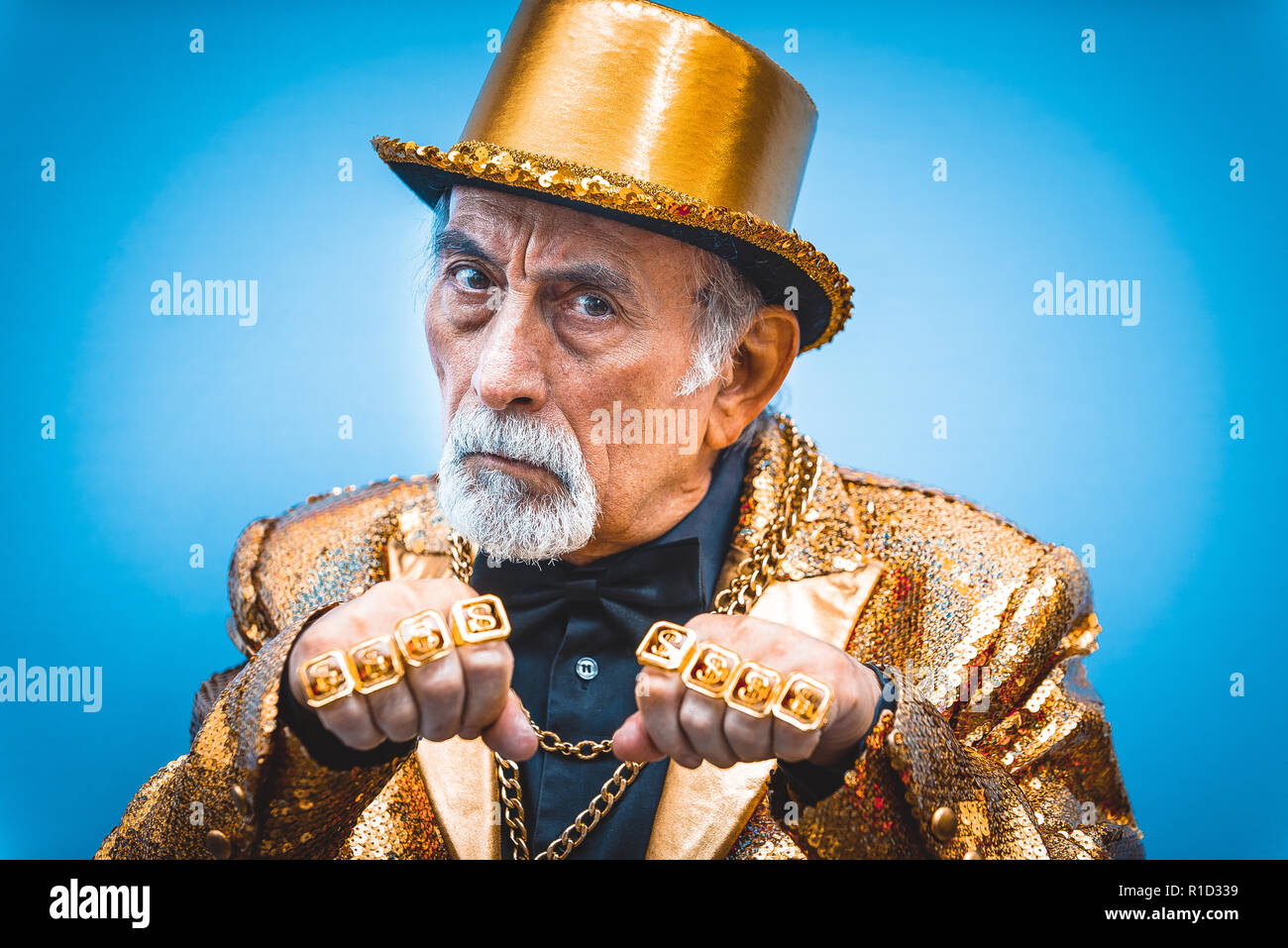 Funny and extravagant senior man posing on colored background ...