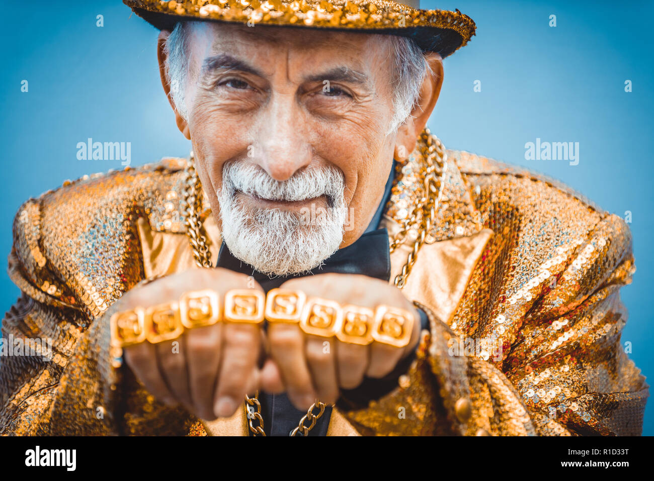 Funny and extravagant senior man posing on colored background ...