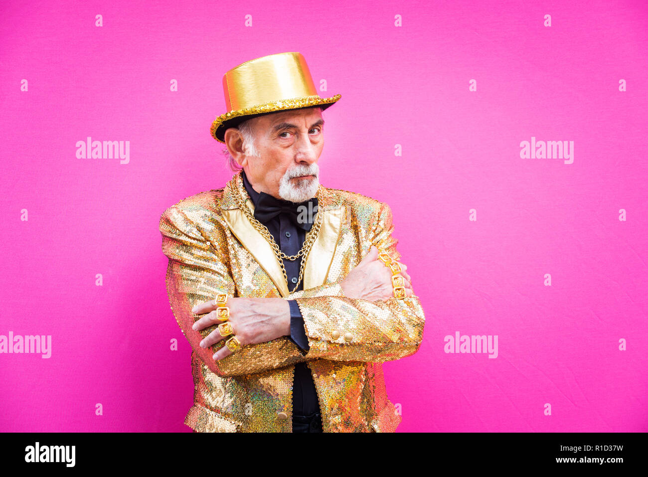 Funny and extravagant senior man posing on colored background ...
