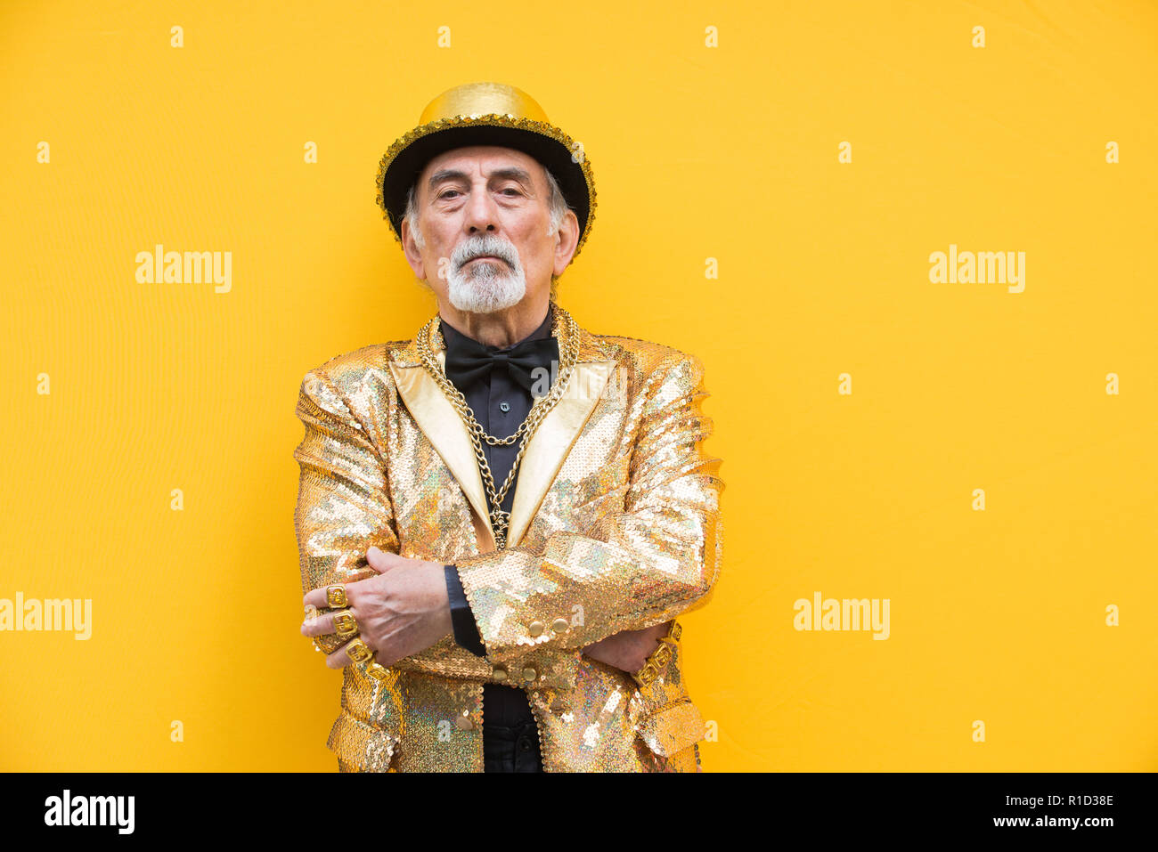 Funny and extravagant senior man posing on colored background ...
