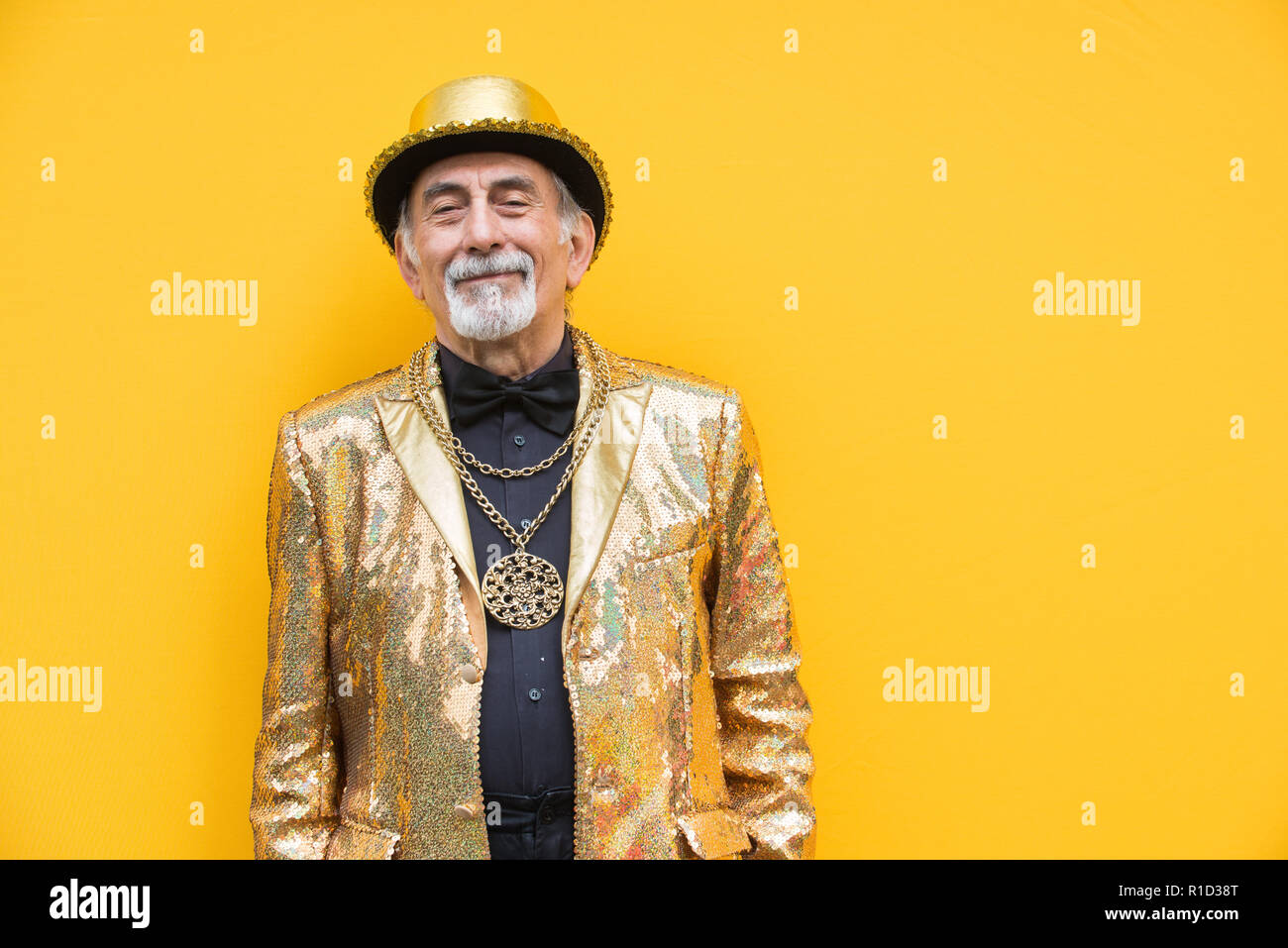 Funny and extravagant senior man posing on colored background ...