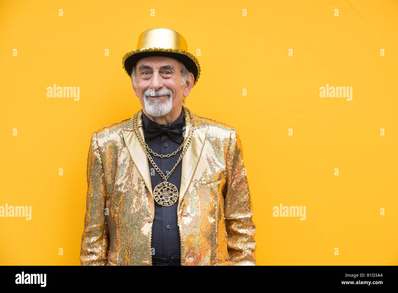 Funny and extravagant senior man posing on colored background ...
