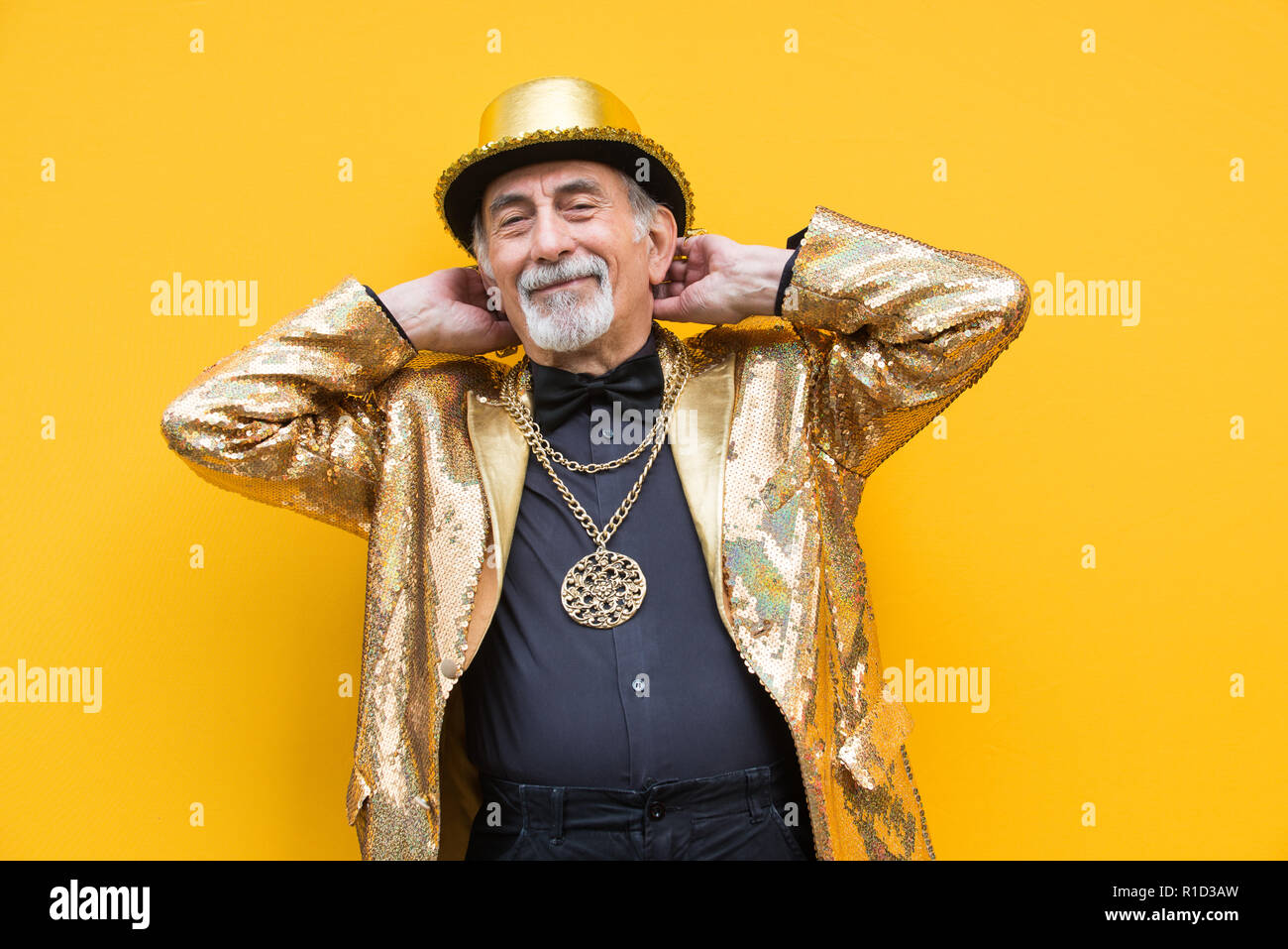 Funny and extravagant senior man posing on colored background ...
