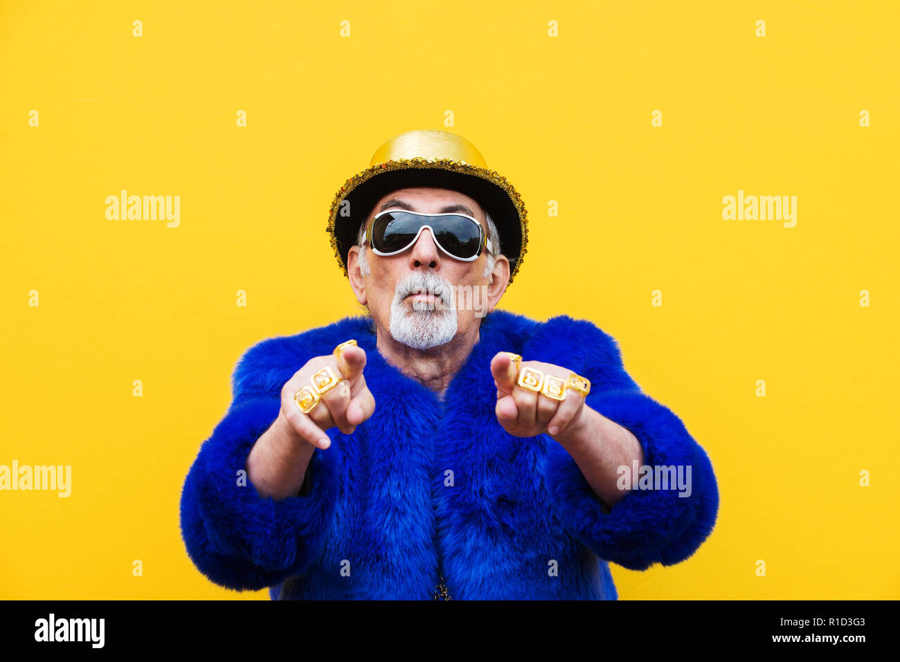 Funny and extravagant senior man posing on colored background ...
